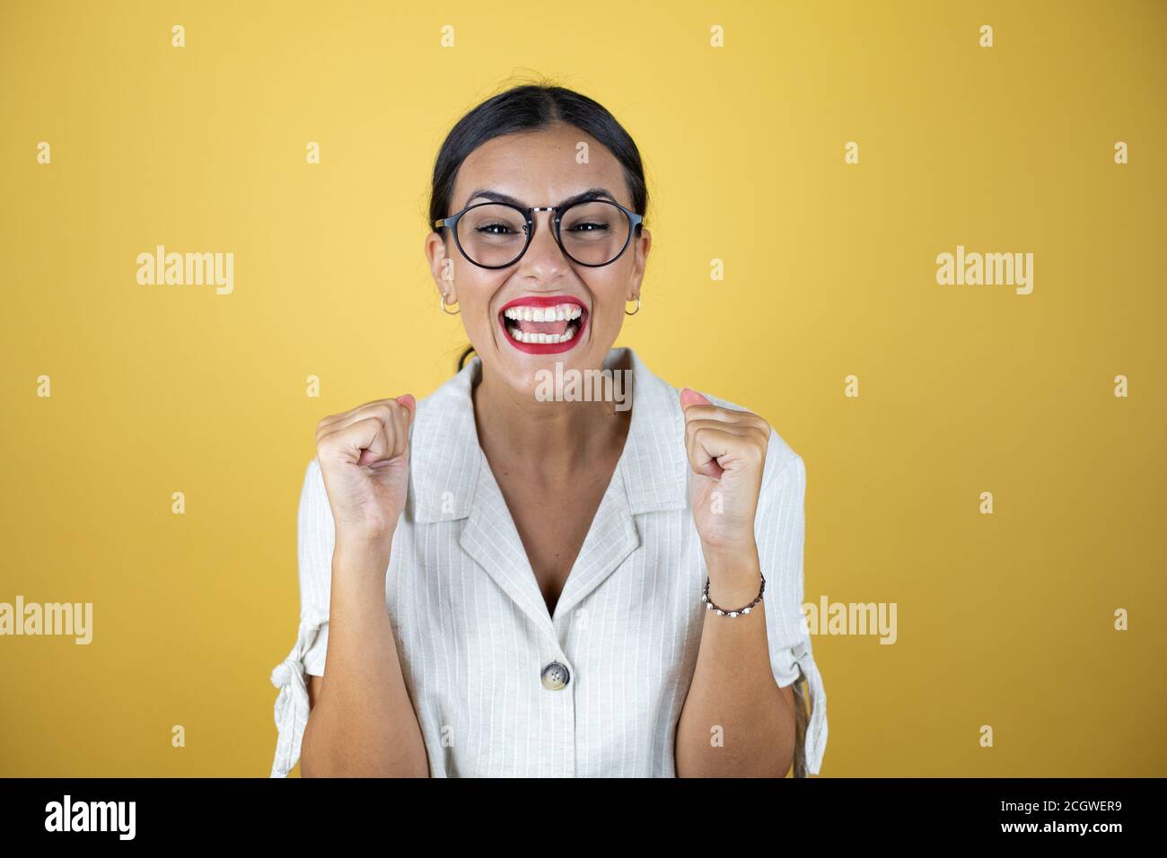 Beautiful woman over yellow background very happy and excited making ...