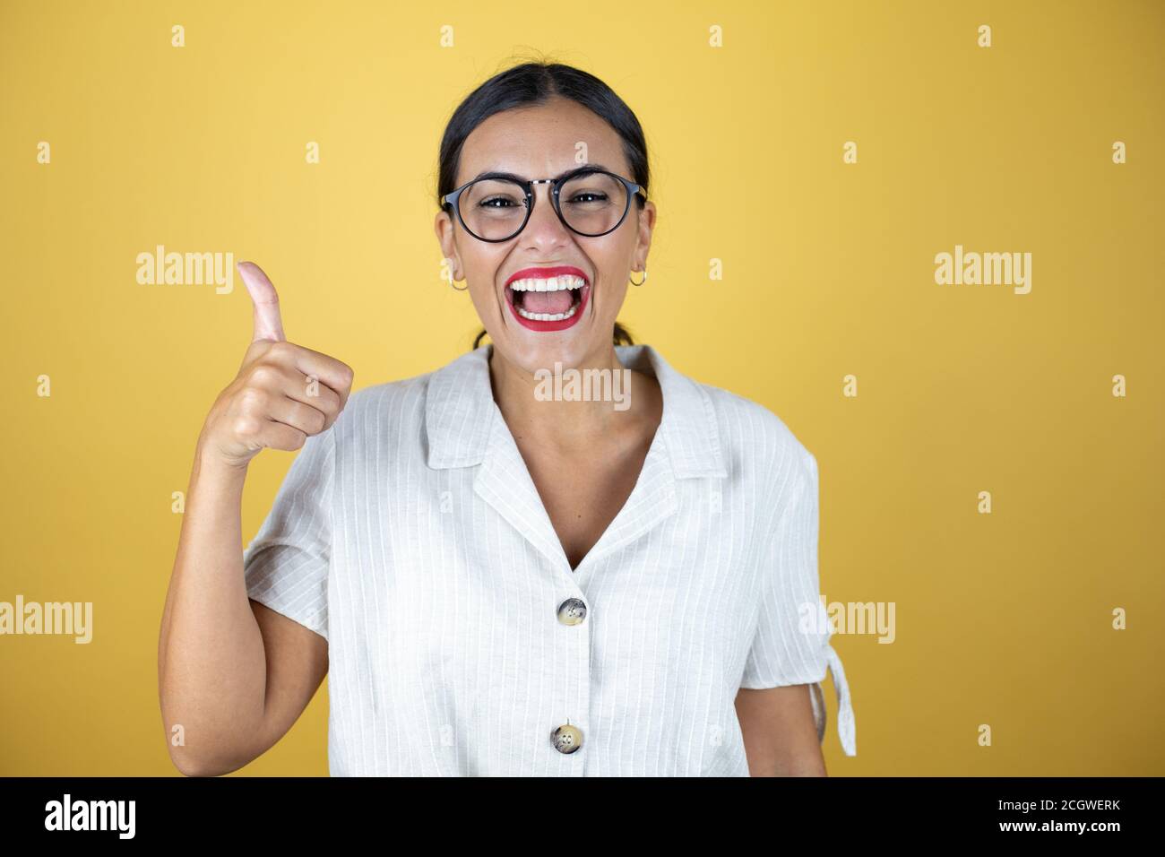 Beautiful woman over yellow background smiling and doing the ok signal ...