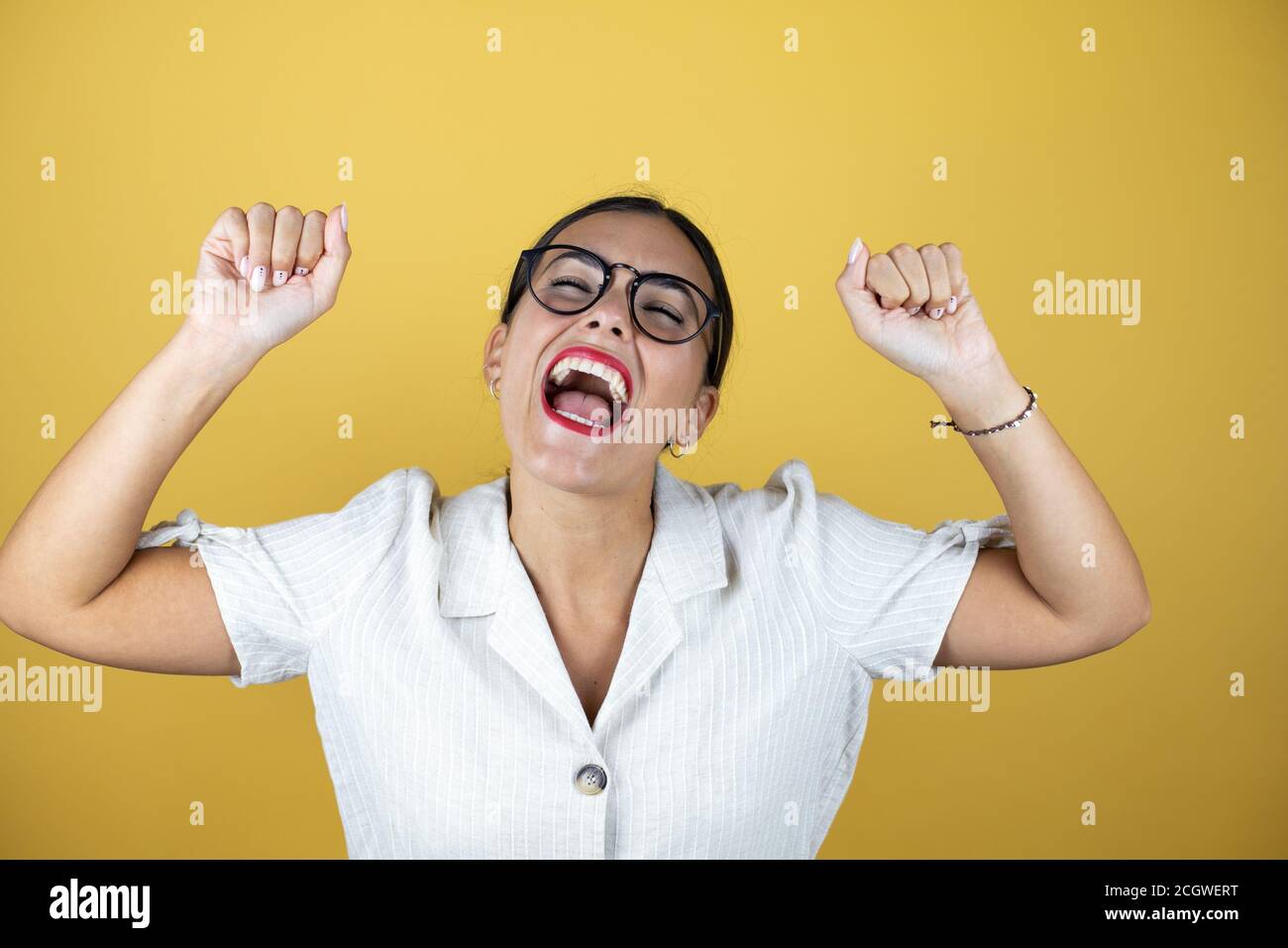 Beautiful woman over yellow background very happy and excited making ...