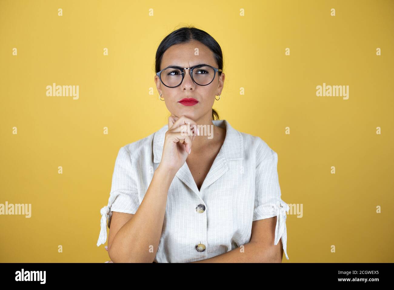 Beautiful woman over yellow background confuse and wonder about ...