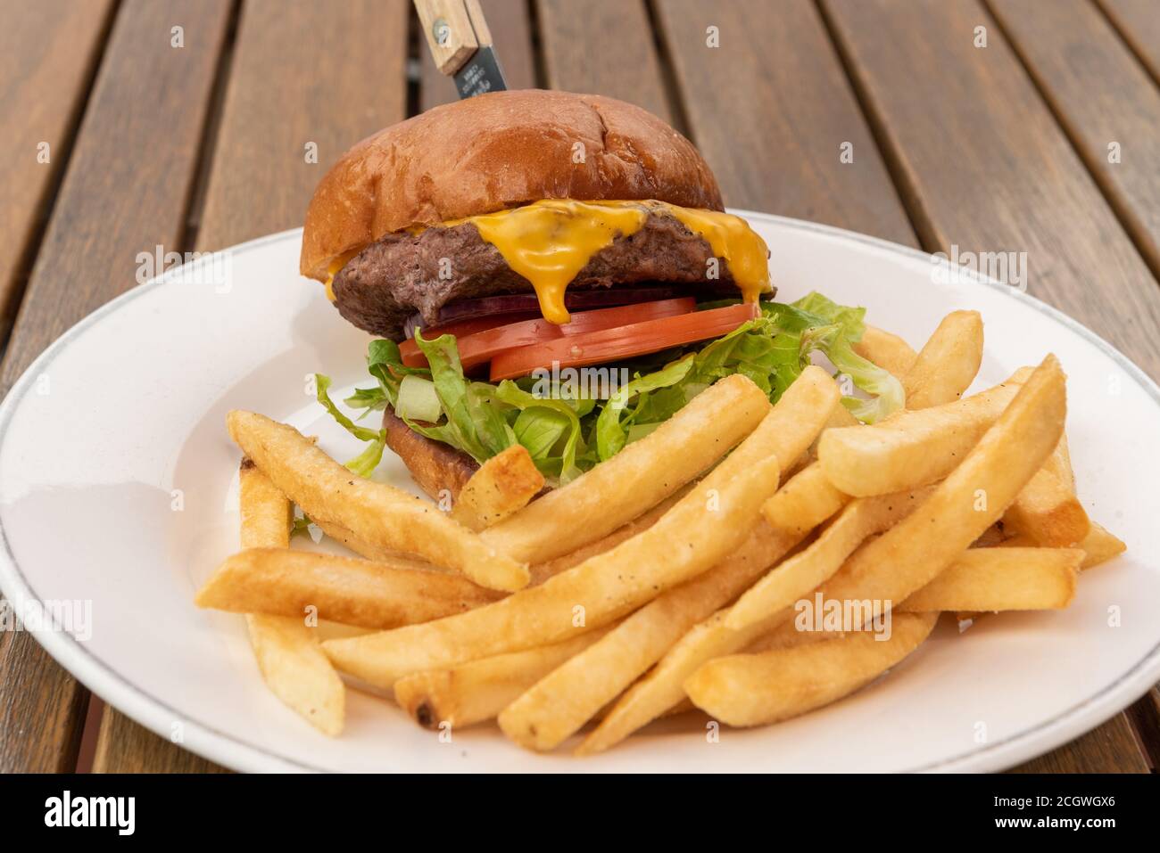 Large and tall cheeseburger topples over from the weight of large patty ...