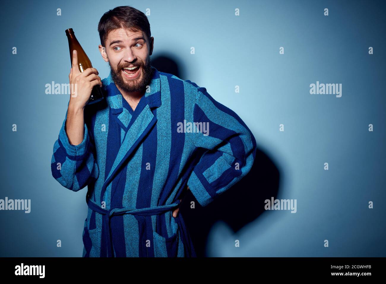 Man alcoholic with a bottle of beer in his hand and in a blue dressing ...