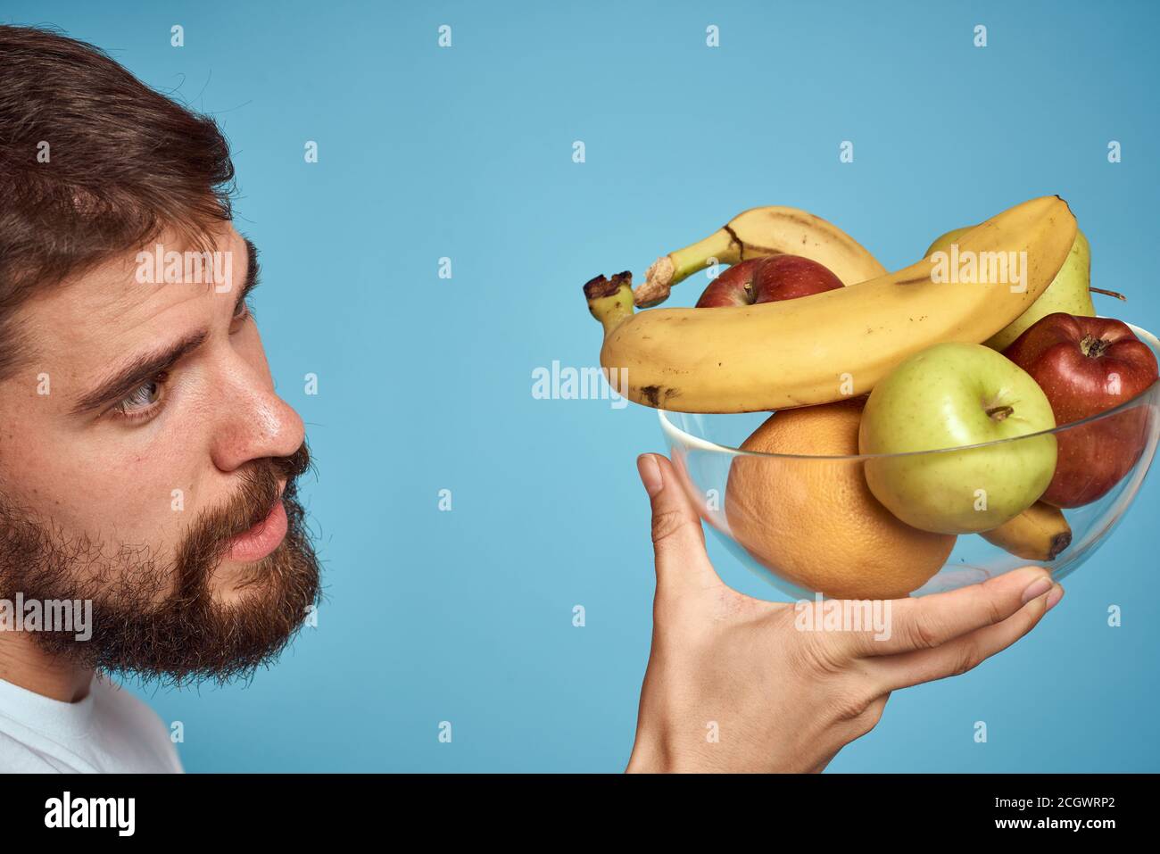 dark background handsome man with a beard holding fresh fruit and ...