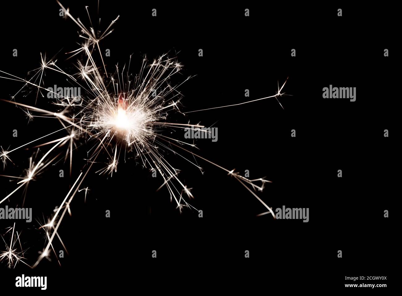 A closeup of a sparkler burning fiercely. Detailed sparks fly in all ...