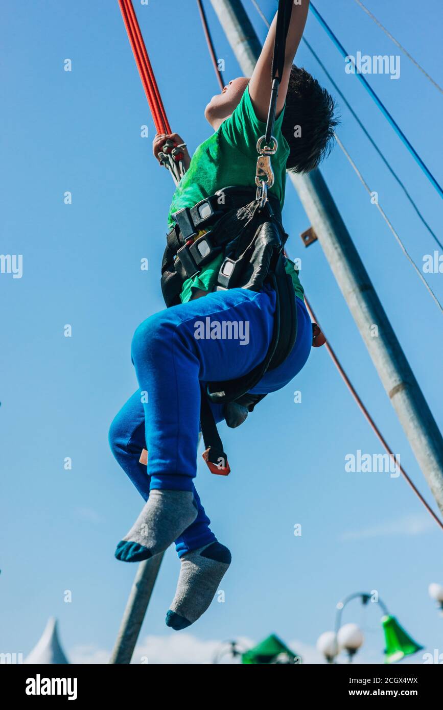 Little cheerful kid playing and having fun on the bungee trampoline ...