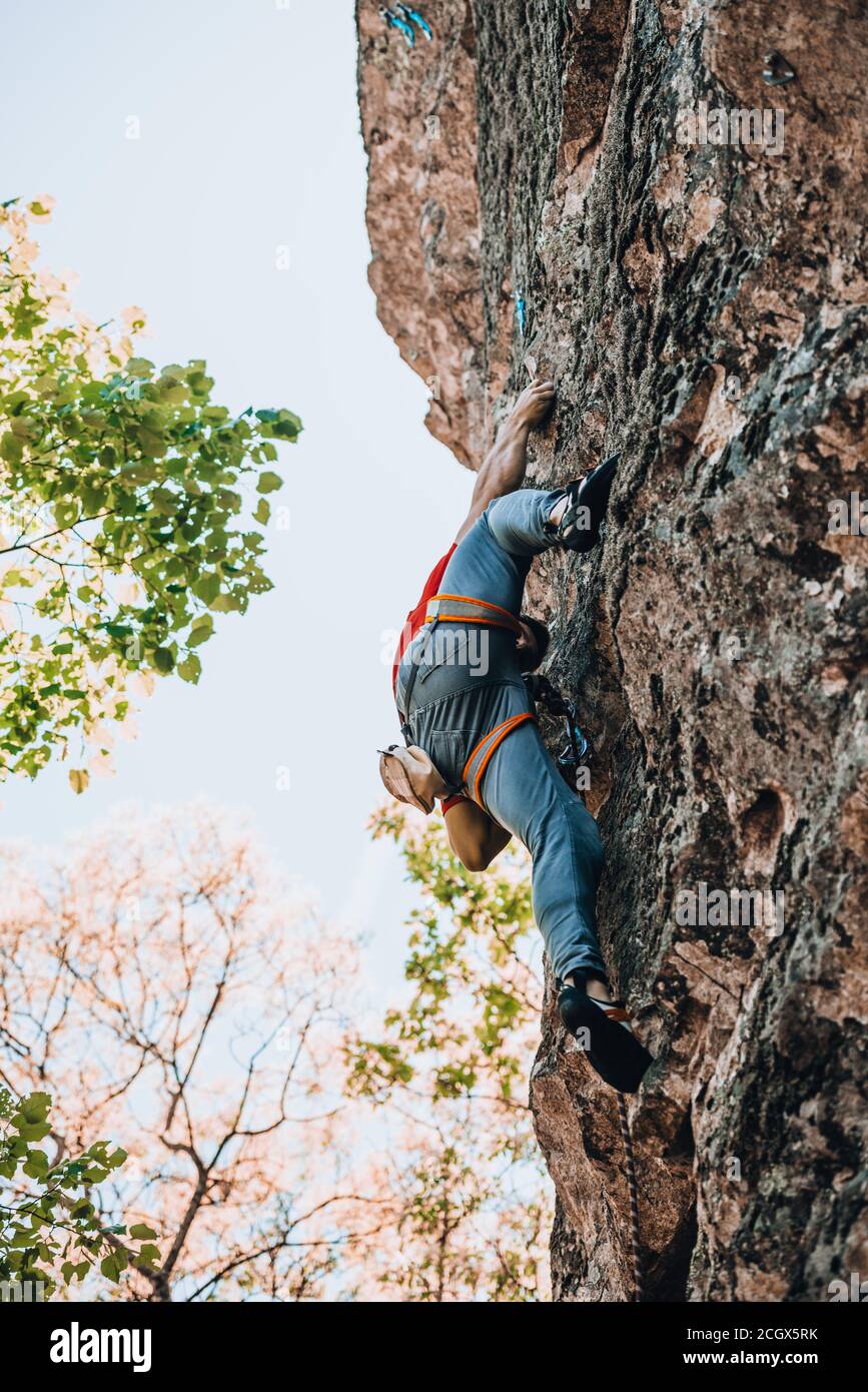 Rock climber ascending a challenging cliff. Extreme sport climbing ...