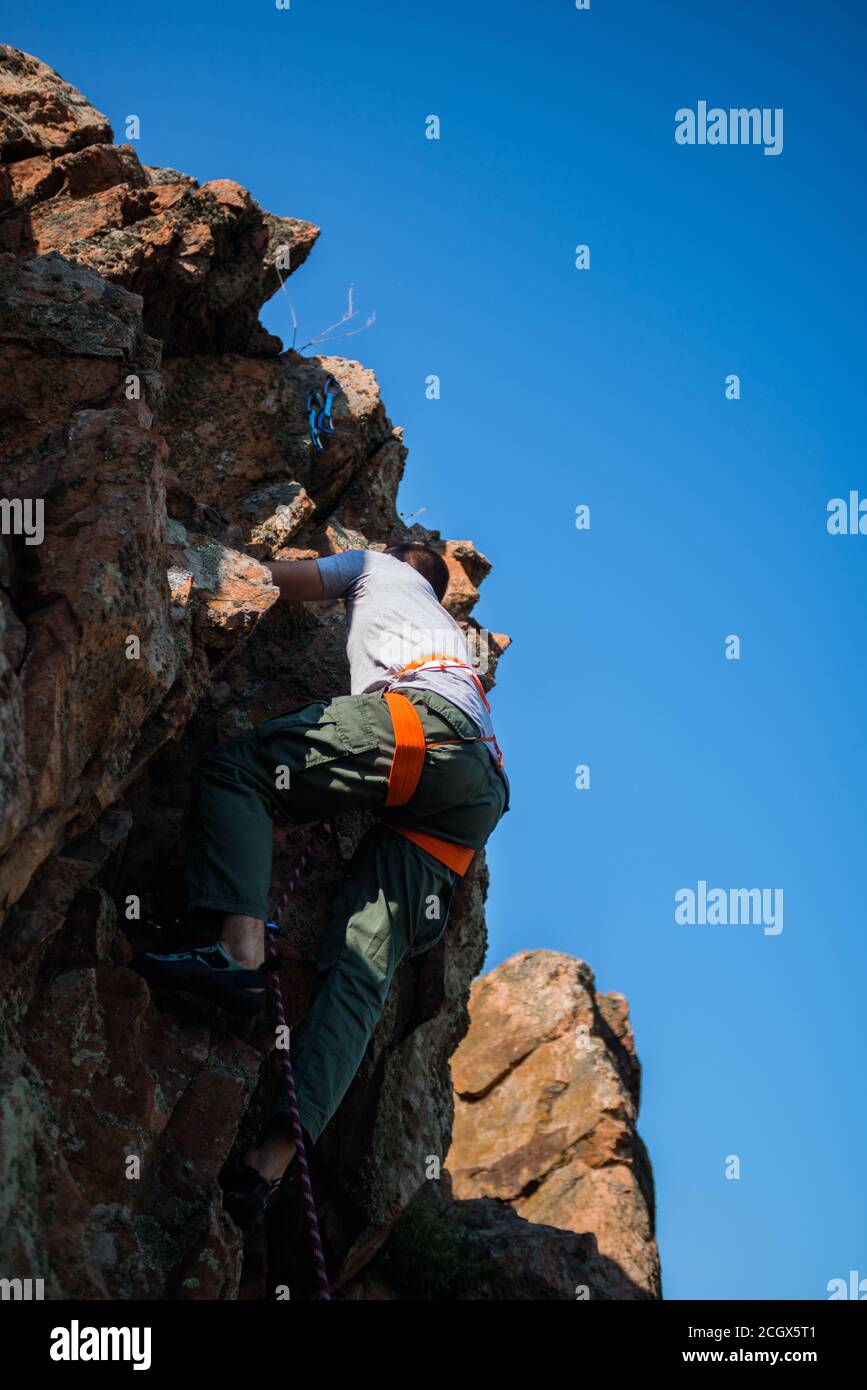Young man climbing on a challenging trail on a cliff practicing for ...