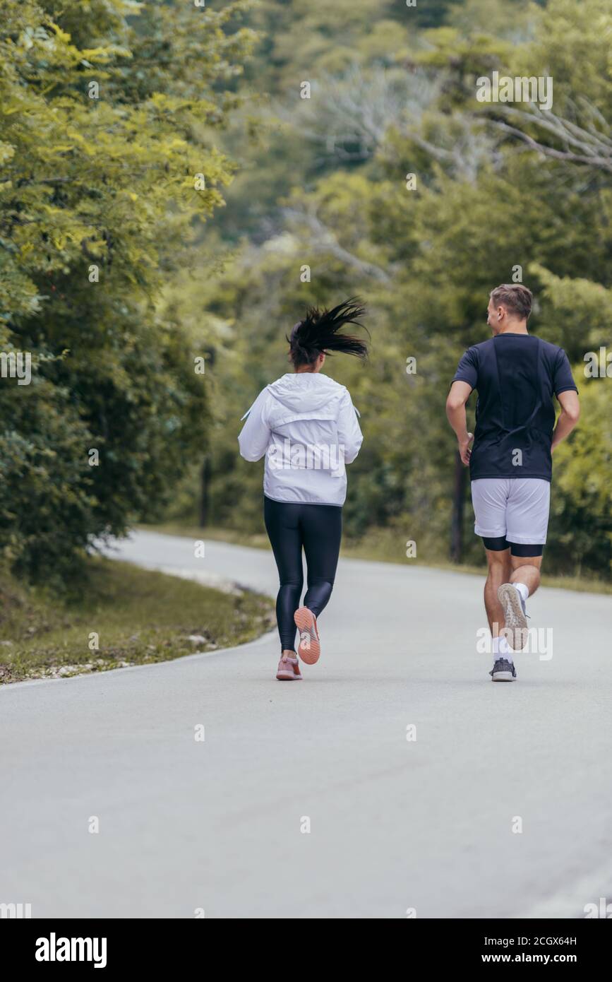 Athletic couple running on a street next to each other. Nature,fit and ...