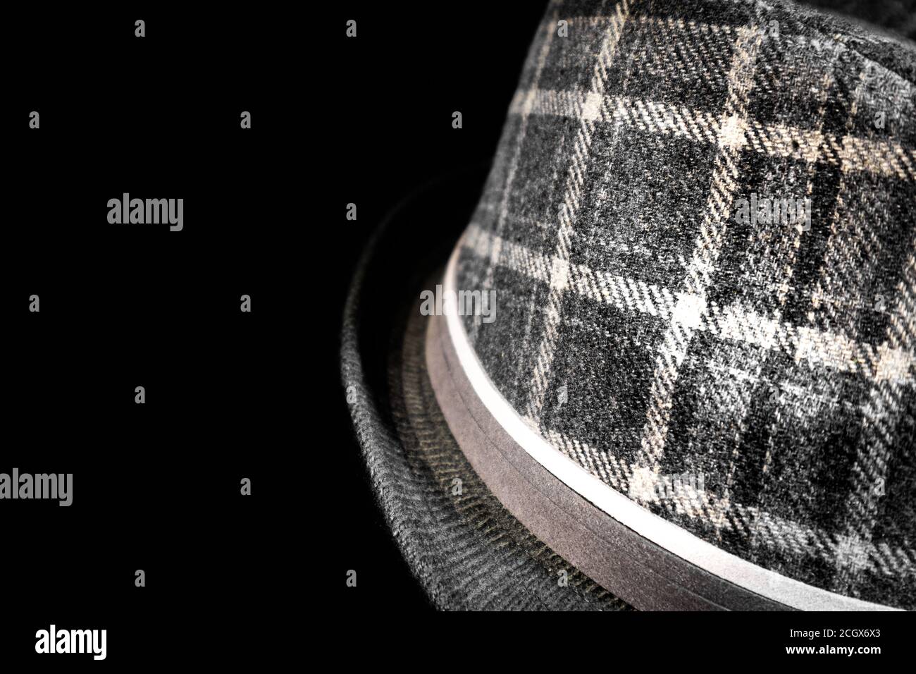 Detail of gray checkered fedora in darkness with small ammount of ...