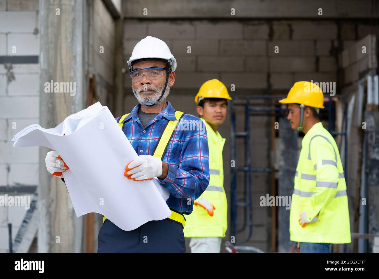 Architect and construction workers working with blue print at ...