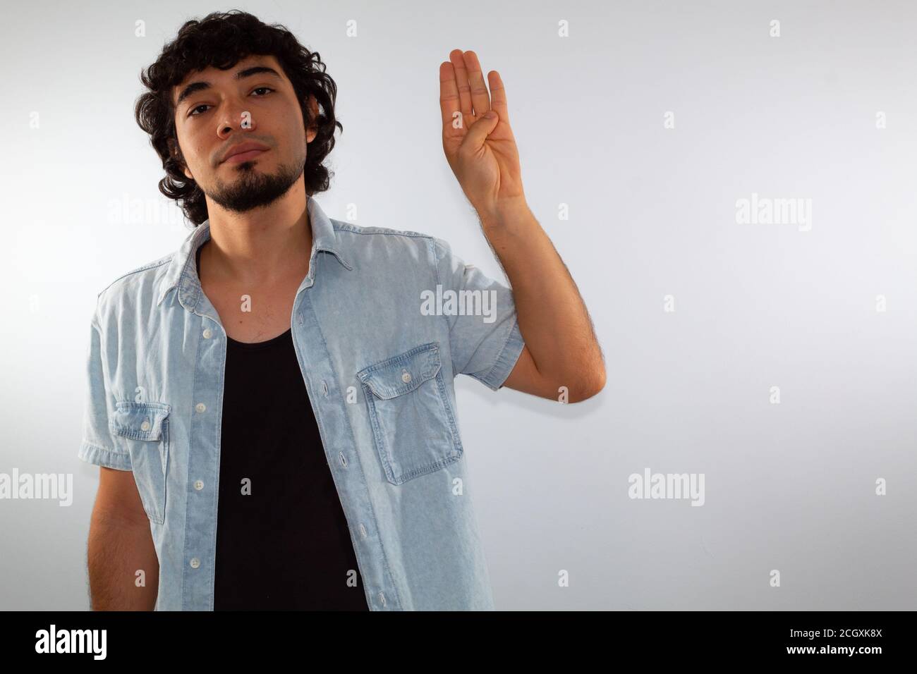 young hispanic deaf man using sign language to communicate, on a white background wearing casual ...
