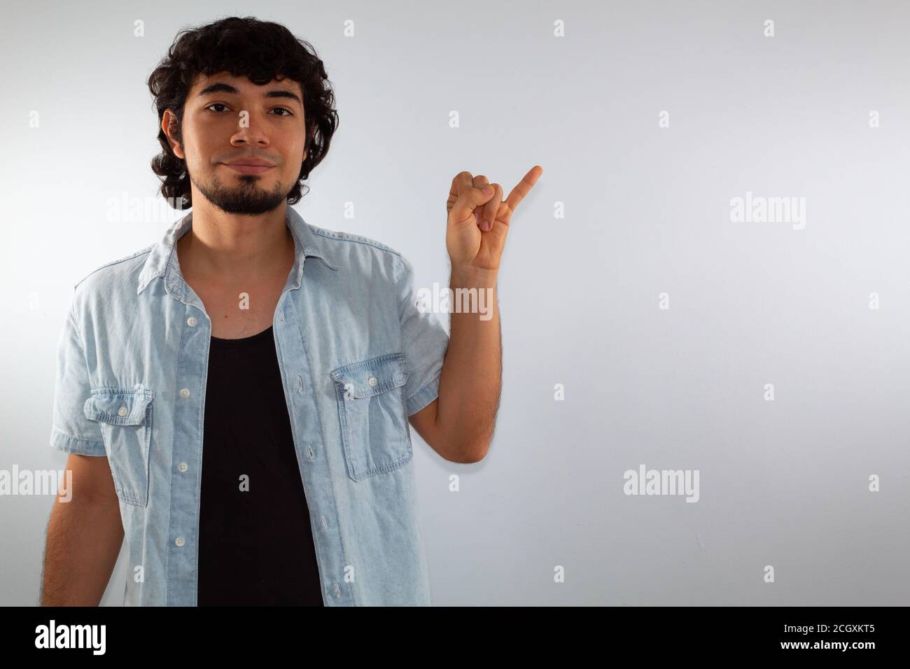 young hispanic deaf man using sign language to communicate, on a white background wearing casual ...