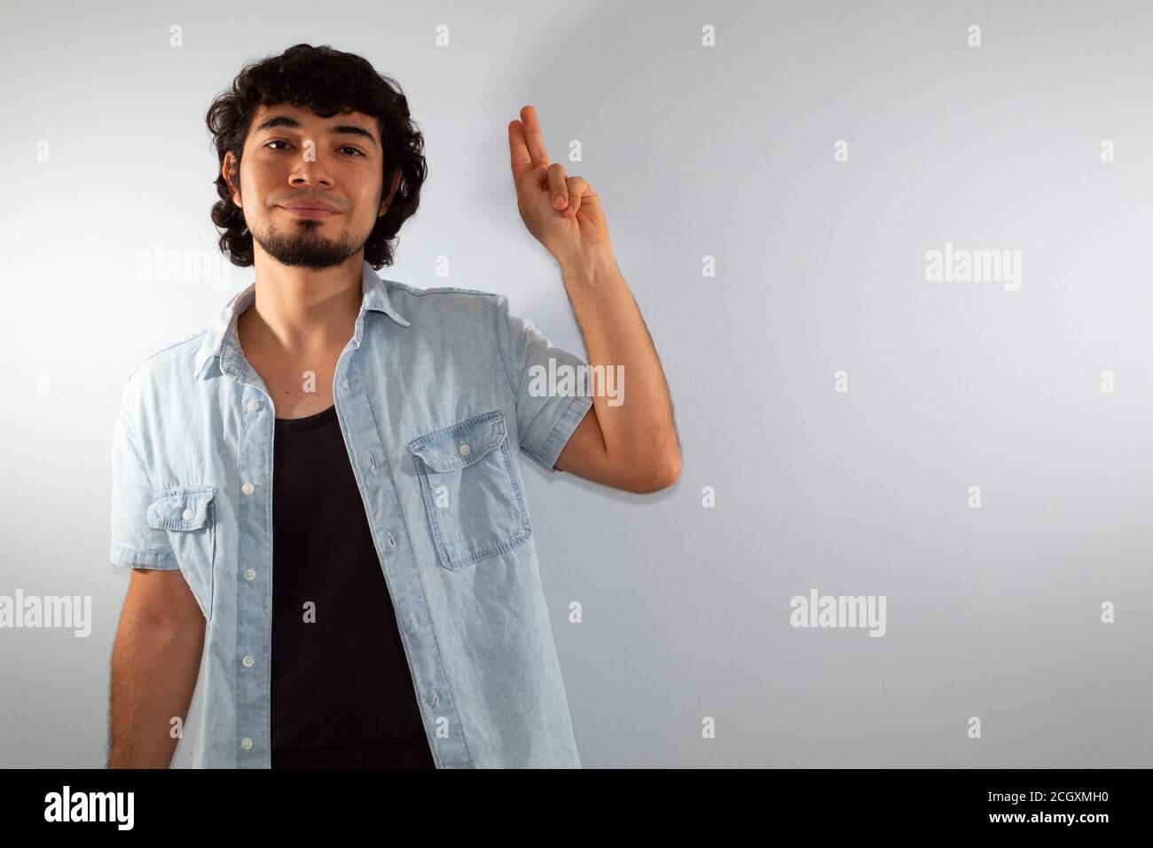 young hispanic deaf man using sign language to communicate, on a white background wearing casual ...