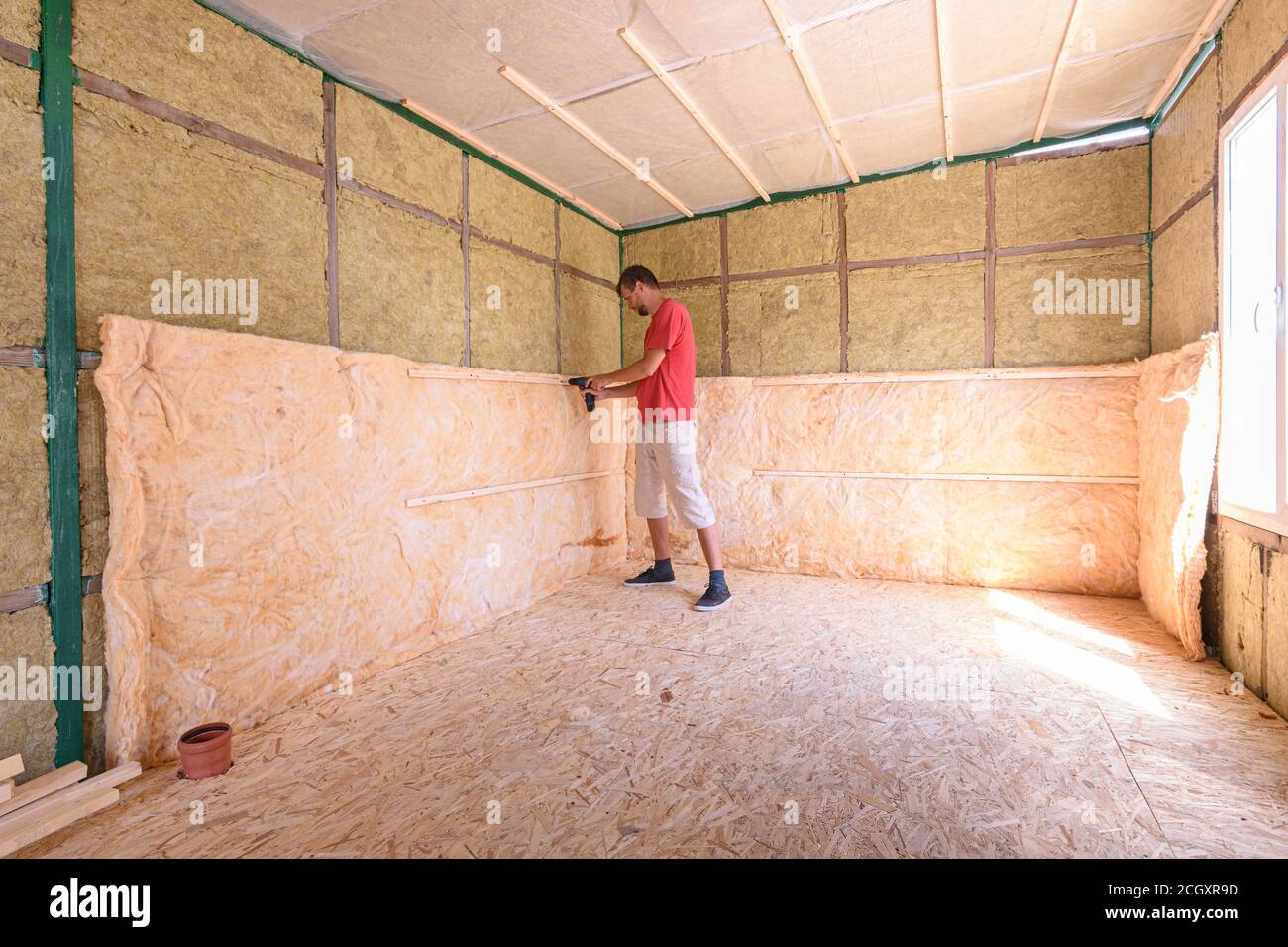 A worker is installing a roll of insulation in the construction of a ...