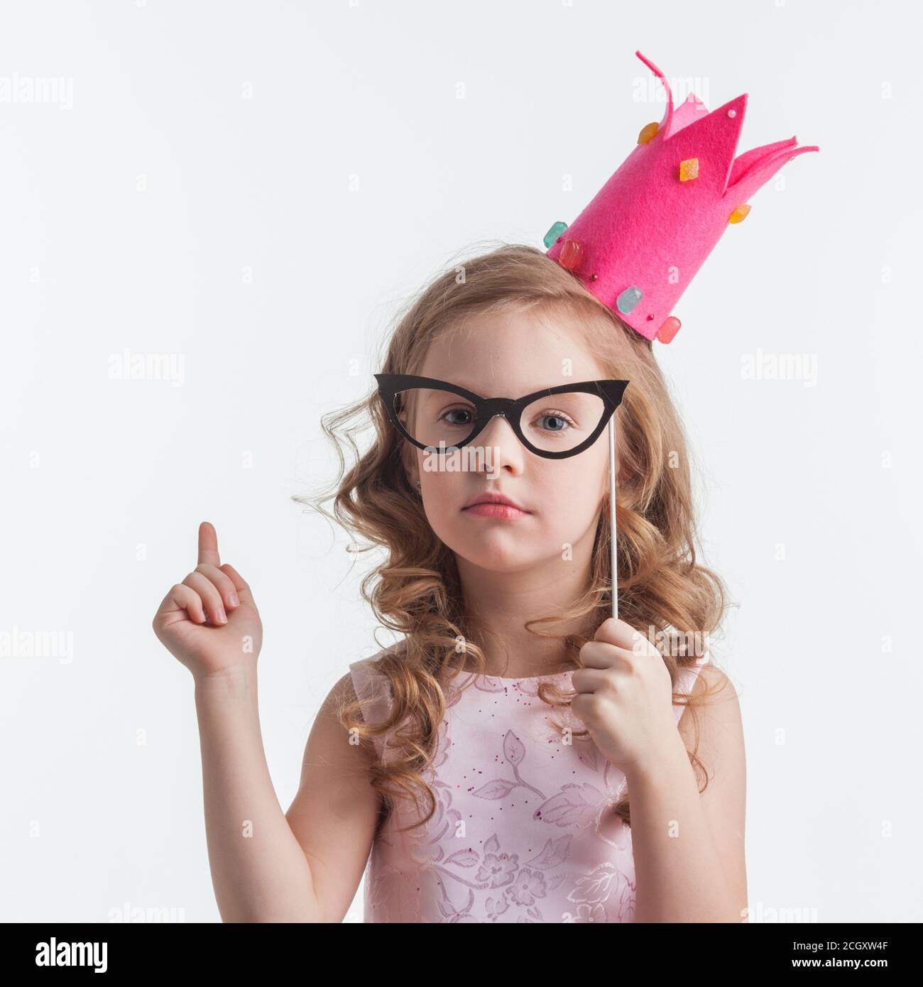 Funny princess girl in pink dress and crown holding party glasses on ...