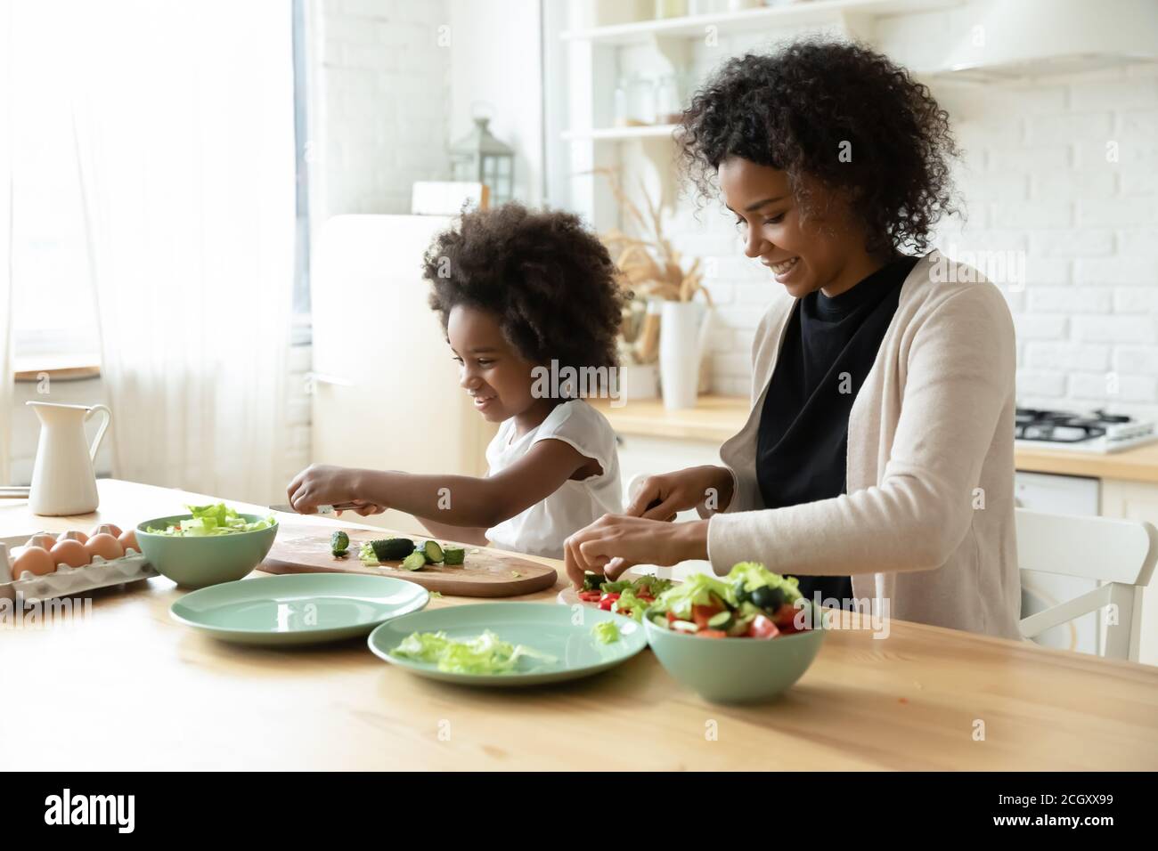 Smiling young african ethnicity woman cooking with small daughter Stock ...