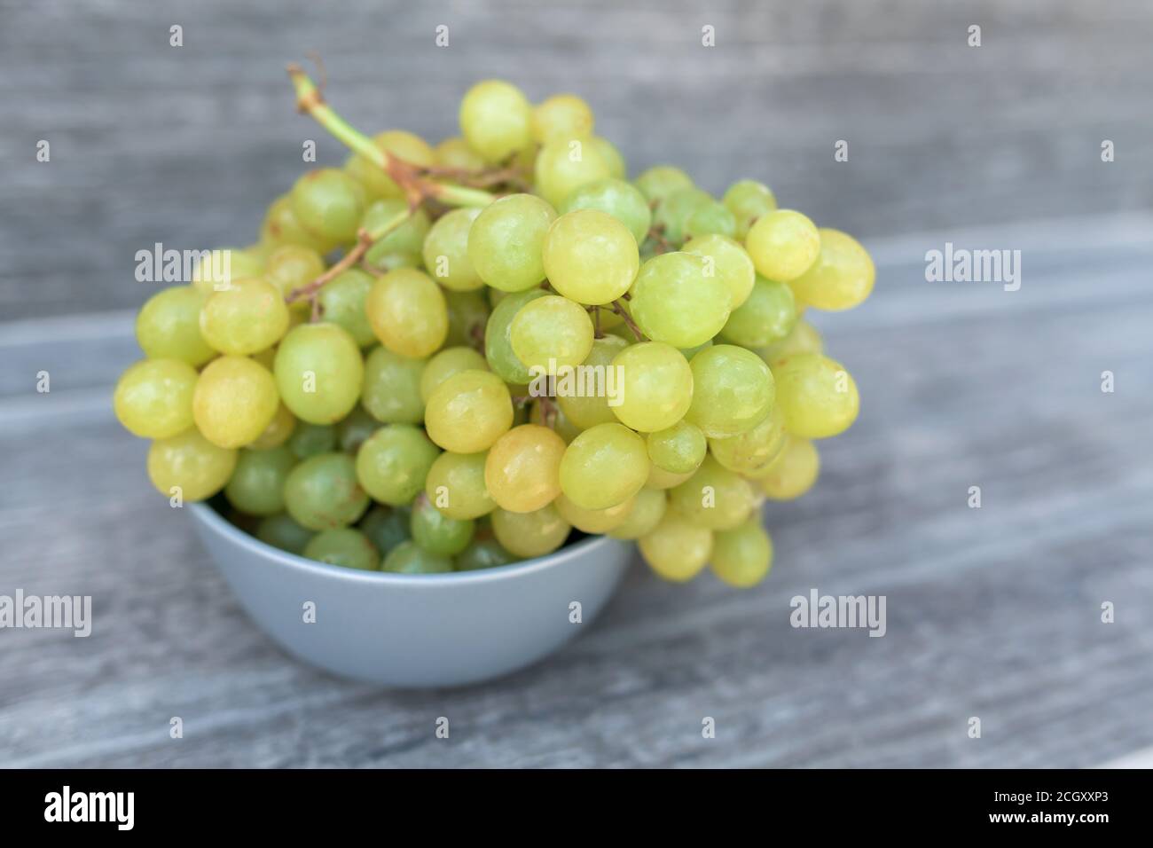 A bunch of ripe green grapes in a gray plat on a gray background Stock ...