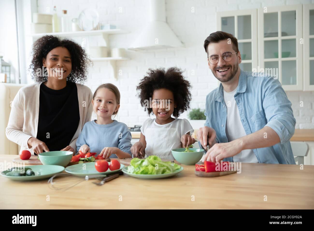 Portrait of happy multiracial family cooking in kitchen with kids Stock ...