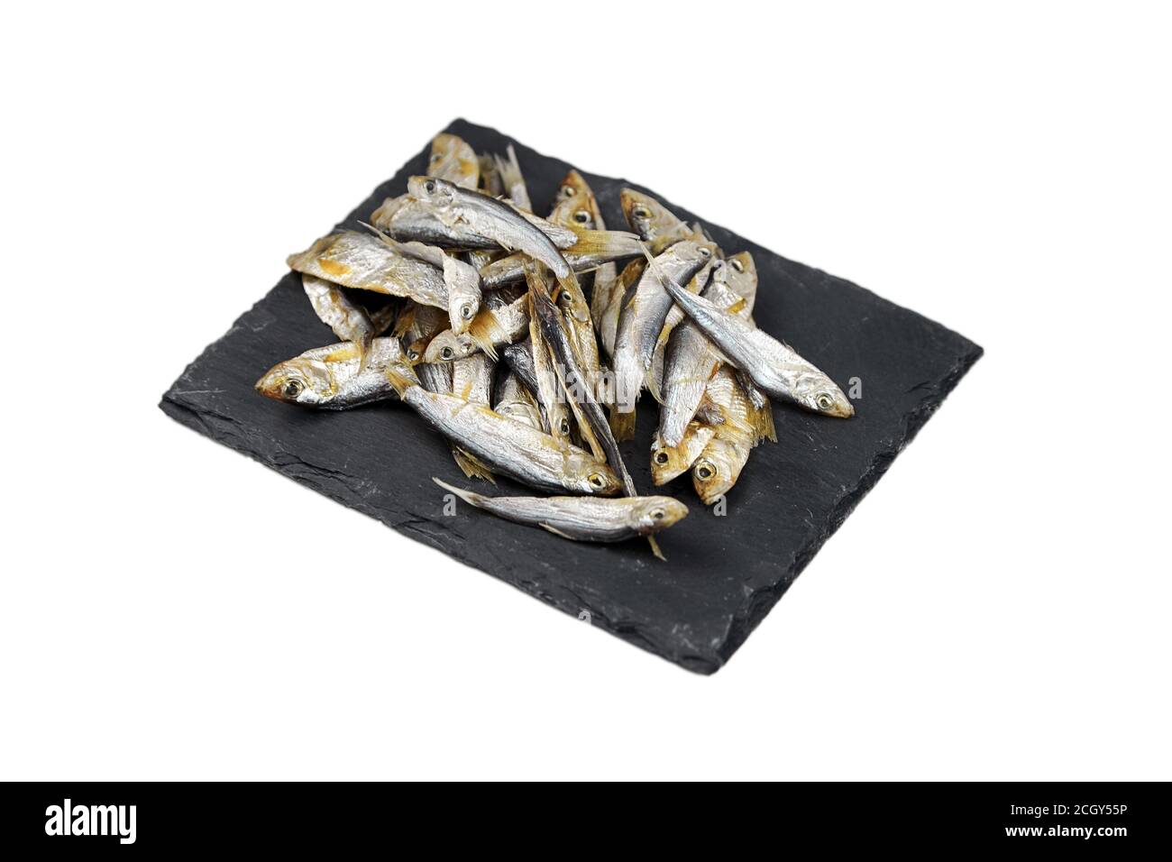Small dried fish on black slate board isolated on white background ...