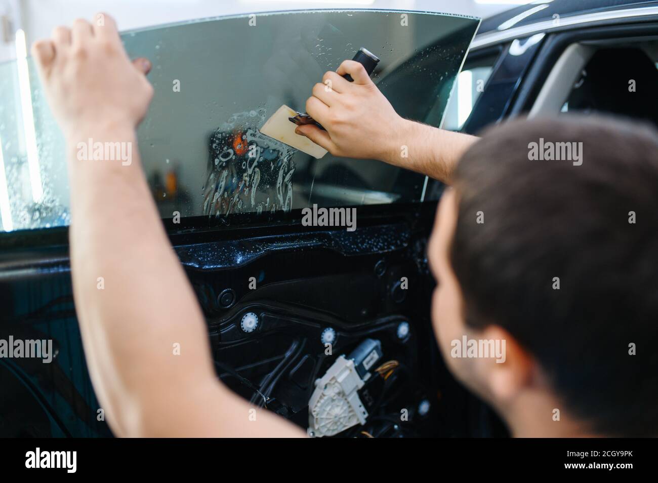 Worker installs wetted car tinting, tuning service Stock Photo - Alamy