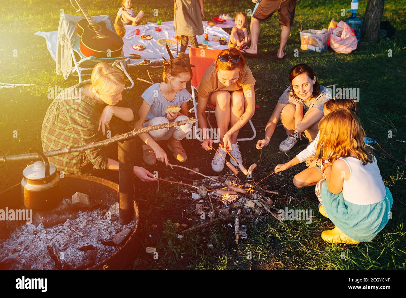 People sitting in a tight circle around bonfire, cooking sausages Stock ...