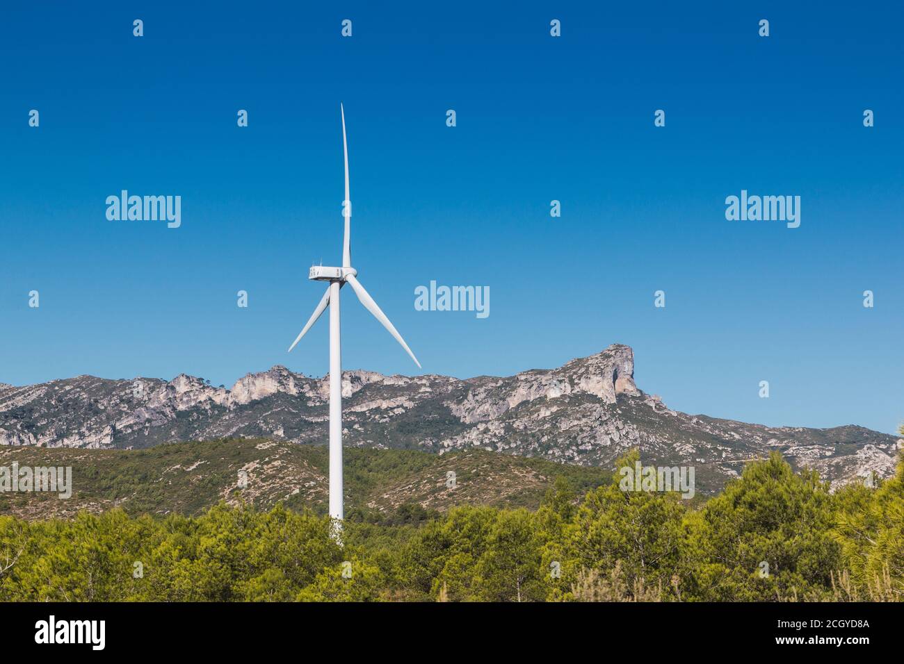 Stock photo of a windmill on top of a wooded mountain and blue sky. It ...