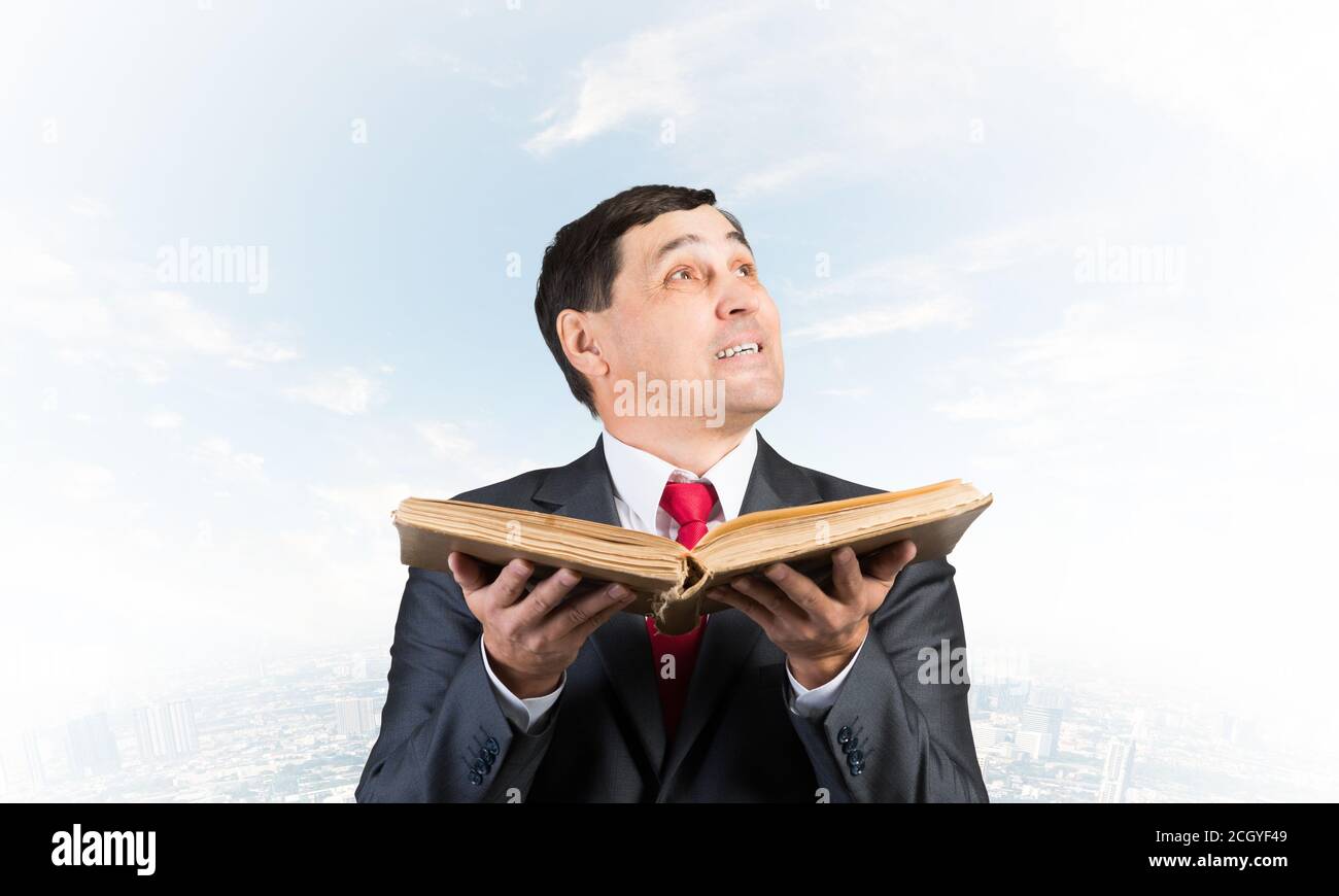 Serious businessman with open book looking up Stock Photo - Alamy