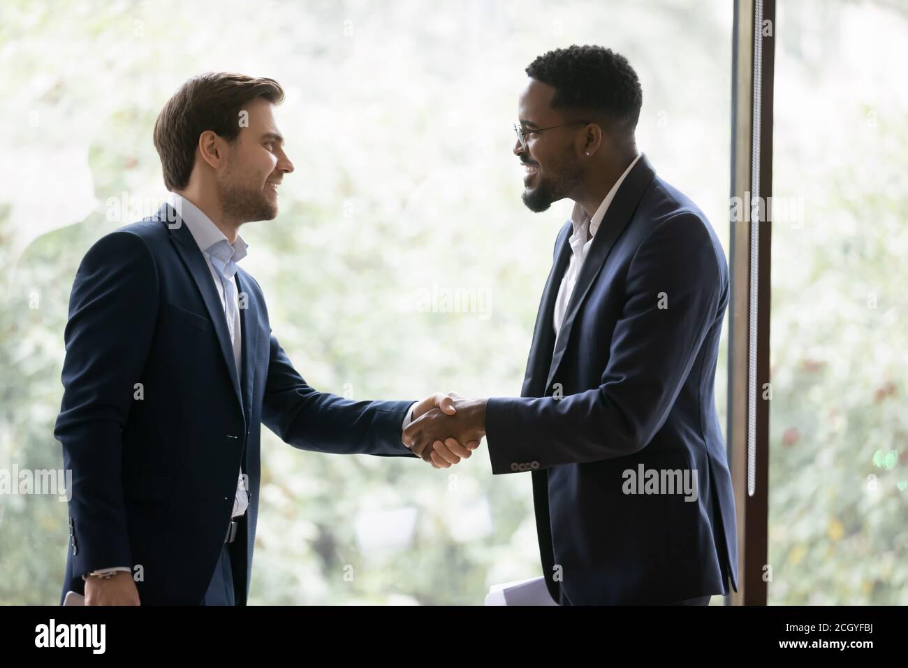 Smiling diverse businessmen handshake closing deal in office Stock ...