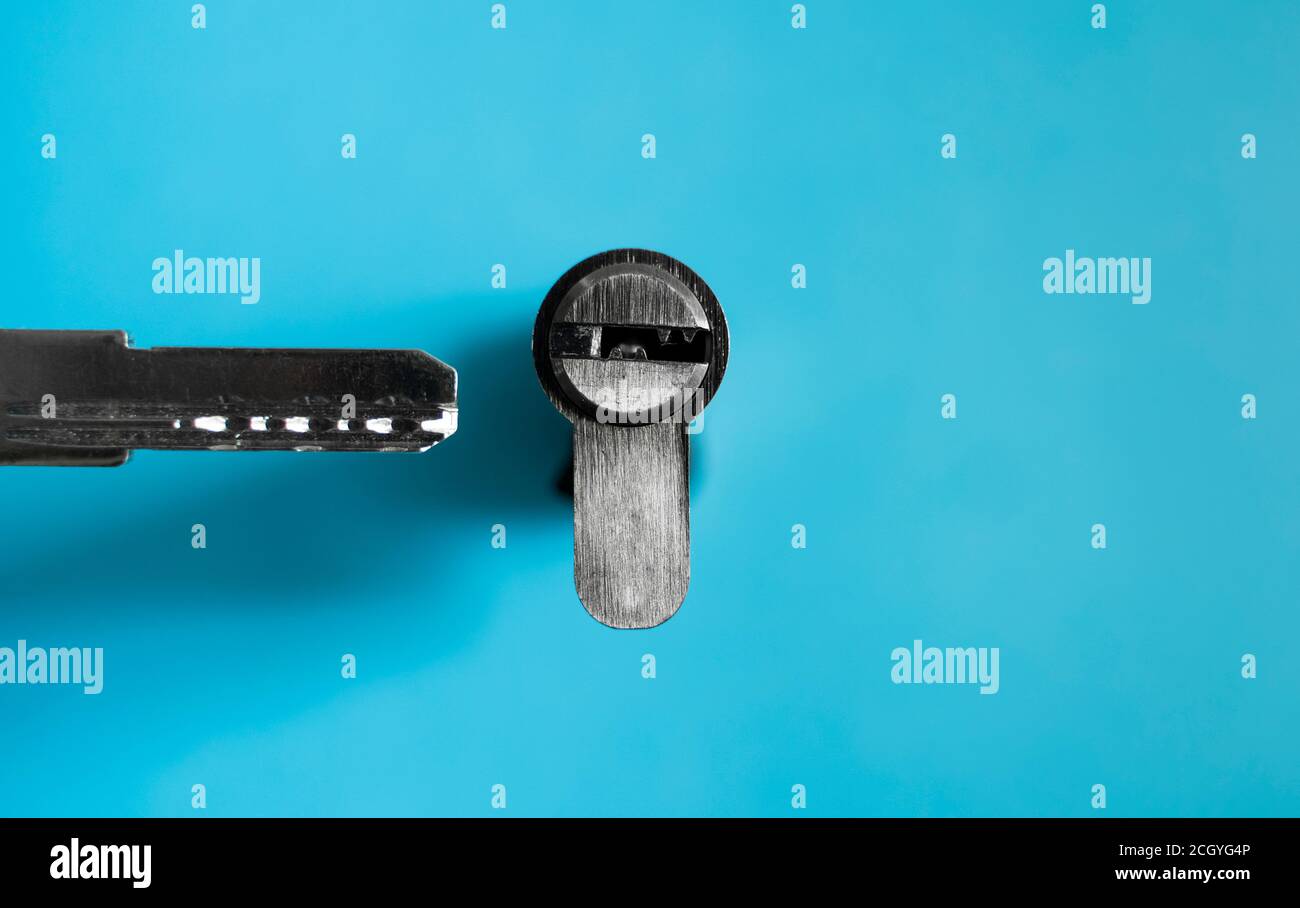 A door lock cylinder core with key on the blue background. The cylinder ...