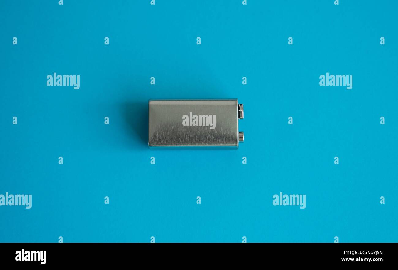 High voltage battery on a blue background. Silver Volt battery. 9V ...