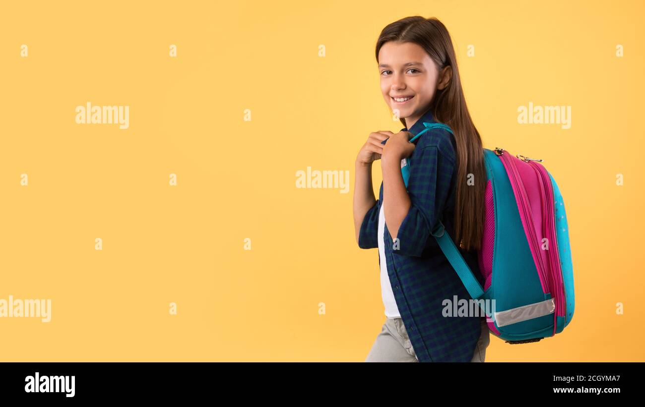 Schoolgirl posing with backpack at studio background Stock Photo - Alamy