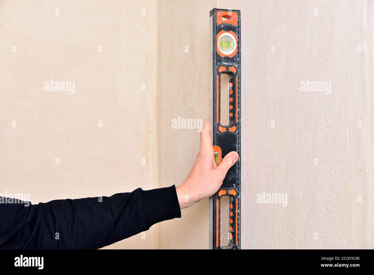 Worker Hand holds spirit level. Check the inclination of the wall with ...