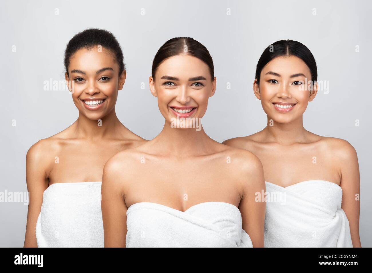 Three Happy Girls Wrapped In Towels Standing On Gray Background Stock ...