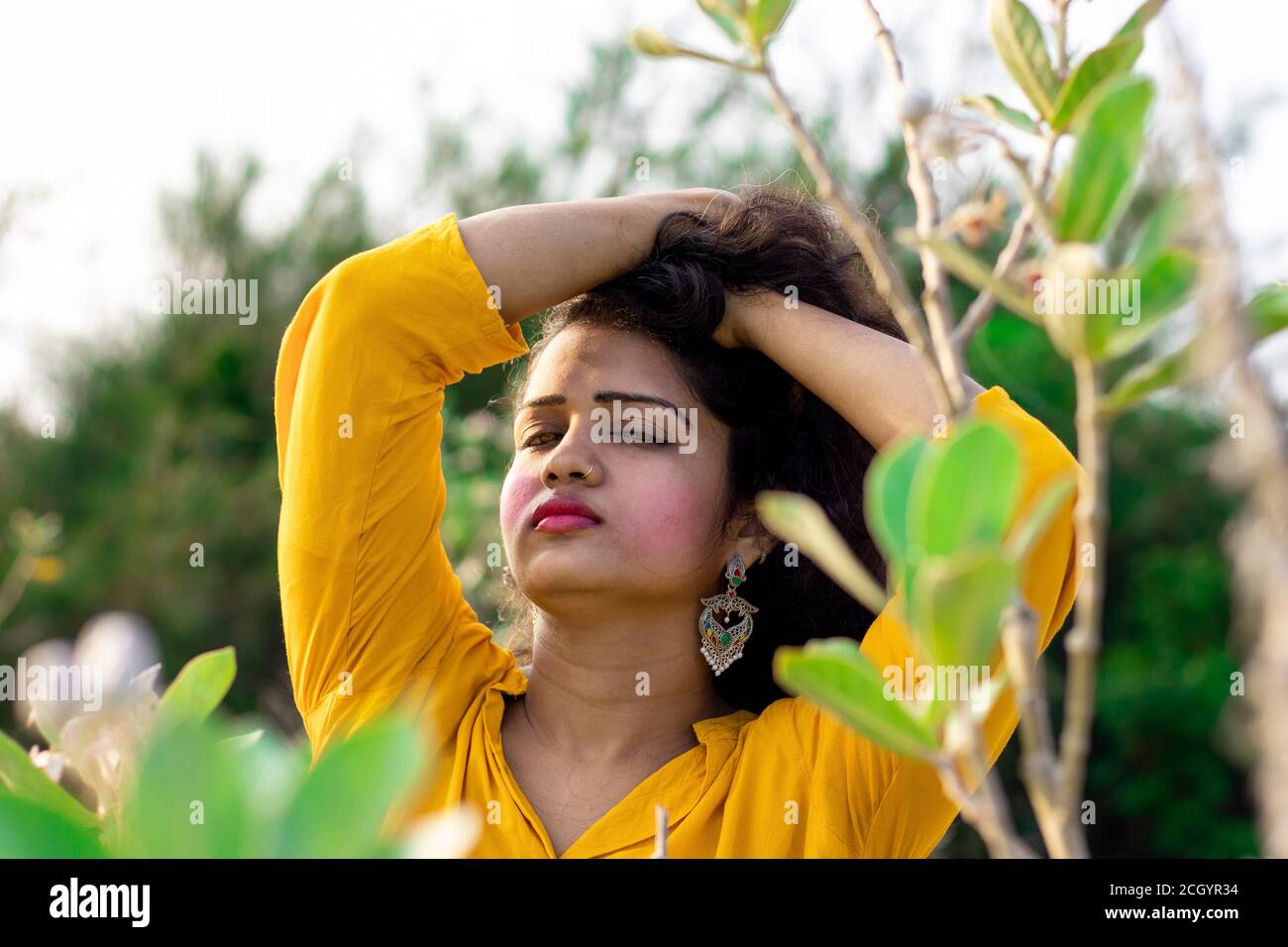 A beautiful Asian woman is standing near the tree of Aak, Madar ...