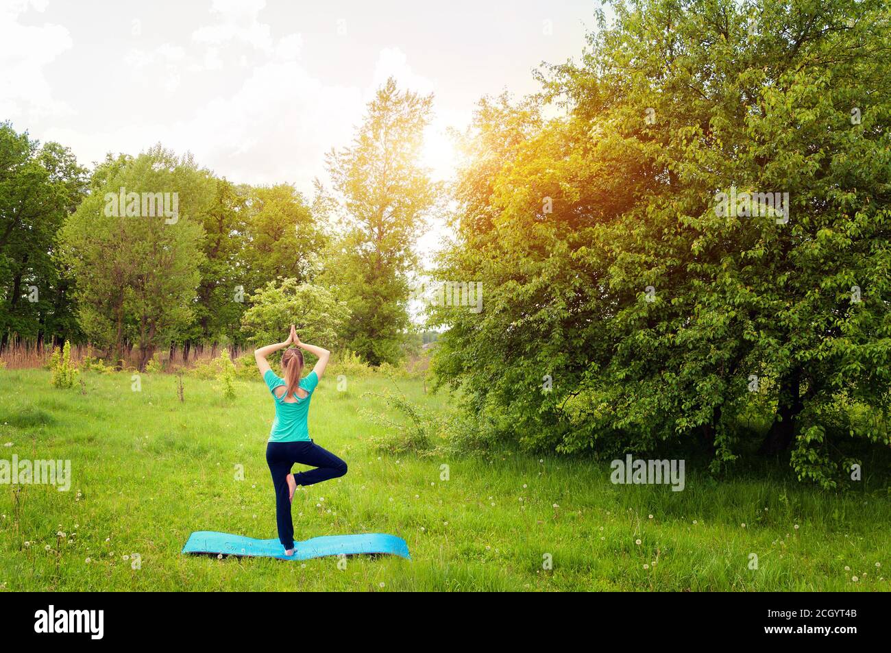 Woman practices yoga outdoor, back side view Stock Photo - Alamy