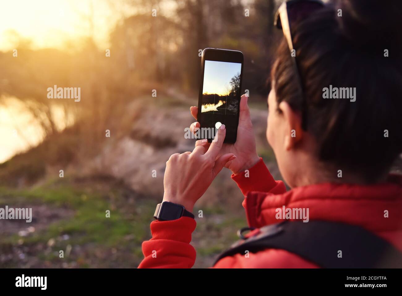 Girl taking landscape with river at sunset time photo with smartphone ...