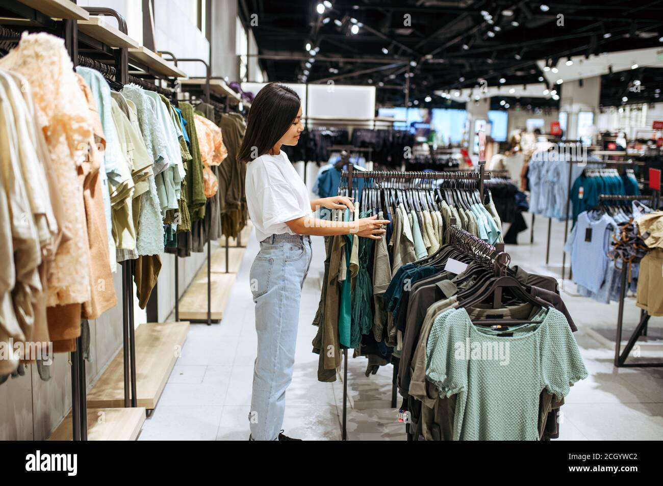 Woman choosing clothes in clothing store Stock Photo - Alamy