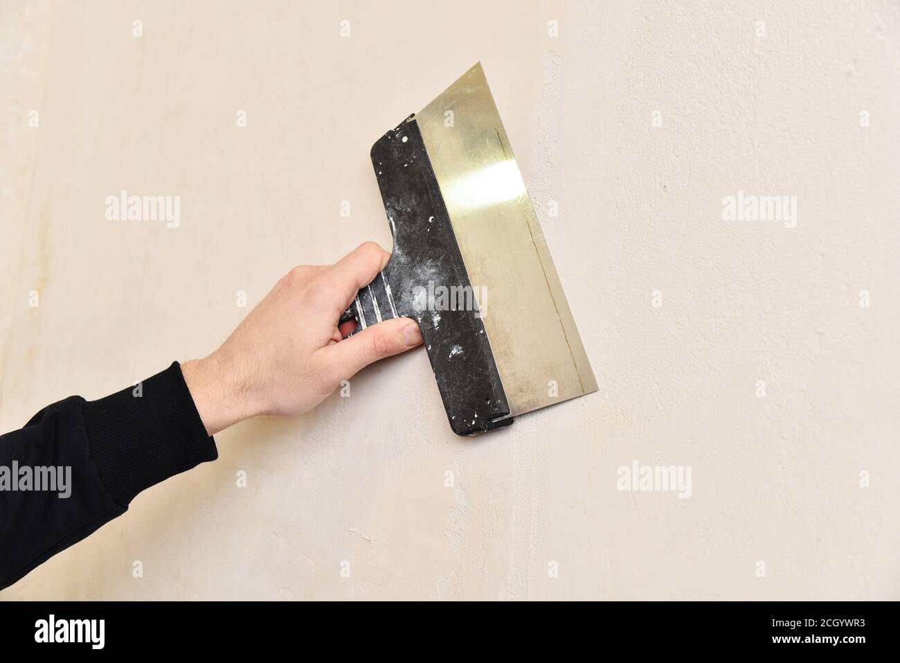 Repair work, puttying the wall with a spatula. Hand holds putty knife ...