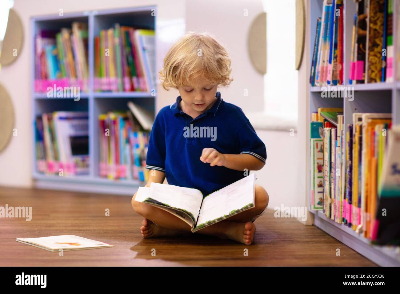 Child in school library. Kids read books. Little boy reading and ...