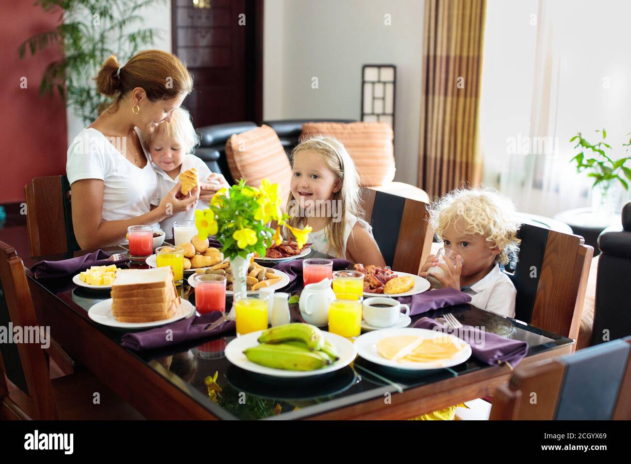 Healthy family breakfast at home. Mother and kids eating tropical fruit ...