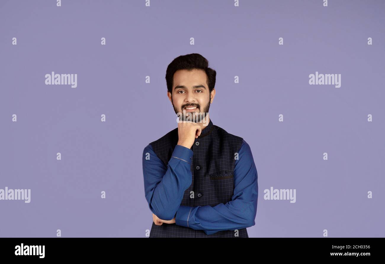 Portrait of attractive Indian man propping chin with his hand on lilac ...