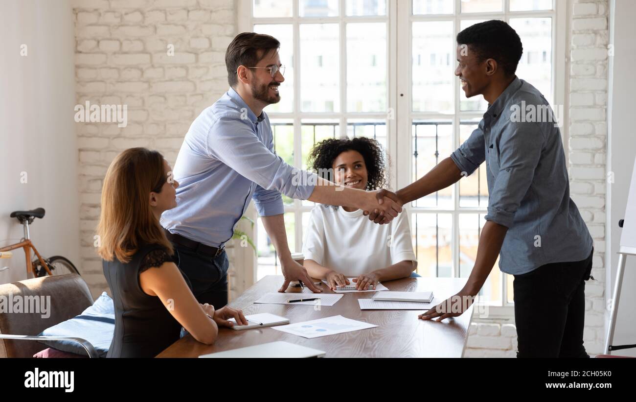 Smiling male colleagues handshake get acquainted at meeting Stock Photo ...
