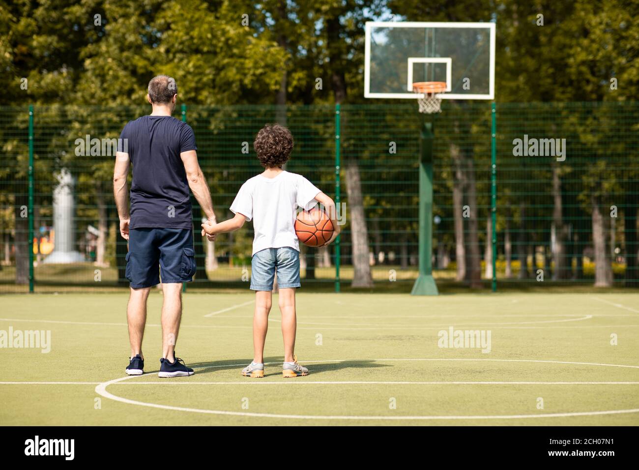 Man posing with son on basketball pitch back view Stock Photo - Alamy
