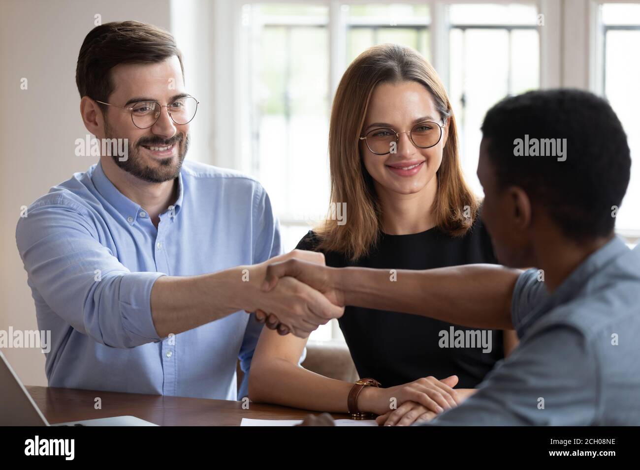 African American realtor handshake happy couple closing deal in office ...