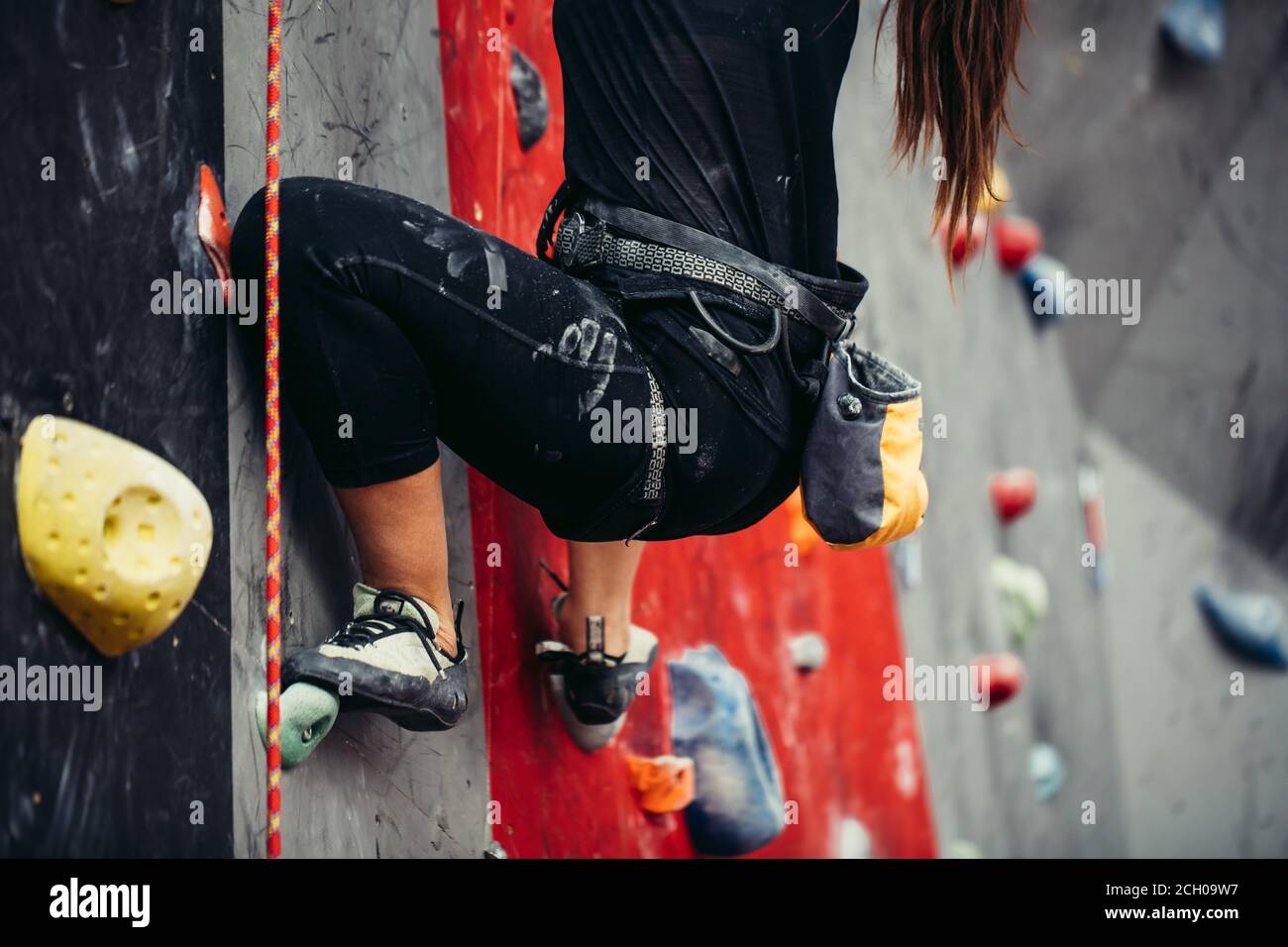 Beautiful young strong woman climbing on rock artificial wall top view ...