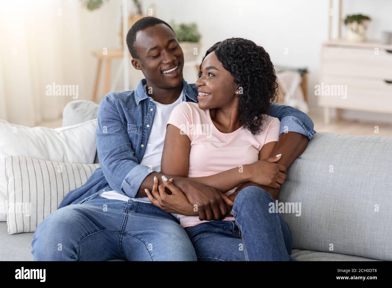 Happy african couple cuddling on sofa at home Stock Photo - Alamy