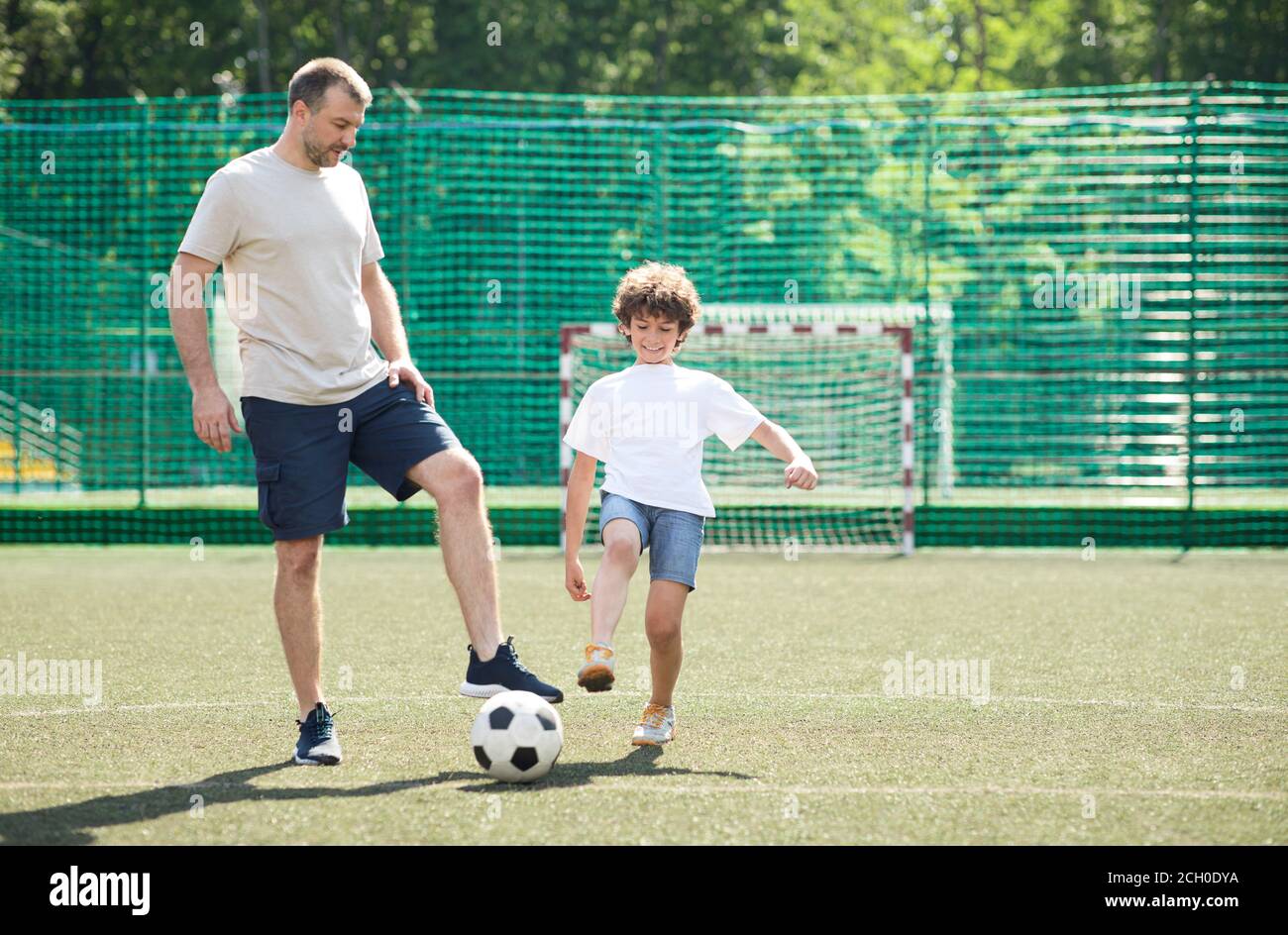 Sportive dad teaching his son how to play football Stock Photo - Alamy