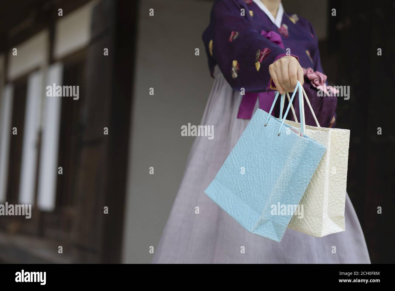 Woman in Korean traditional clothes holding traditional package and shopping bags Stock Photo ...