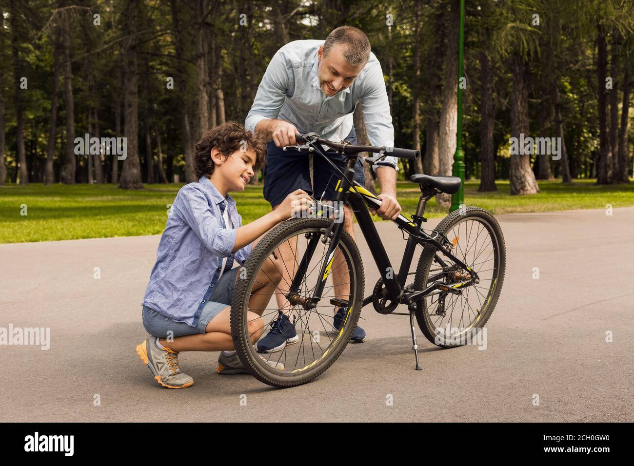 Closeup portrait of cheerful dad and son fixing bike Stock Photo - Alamy