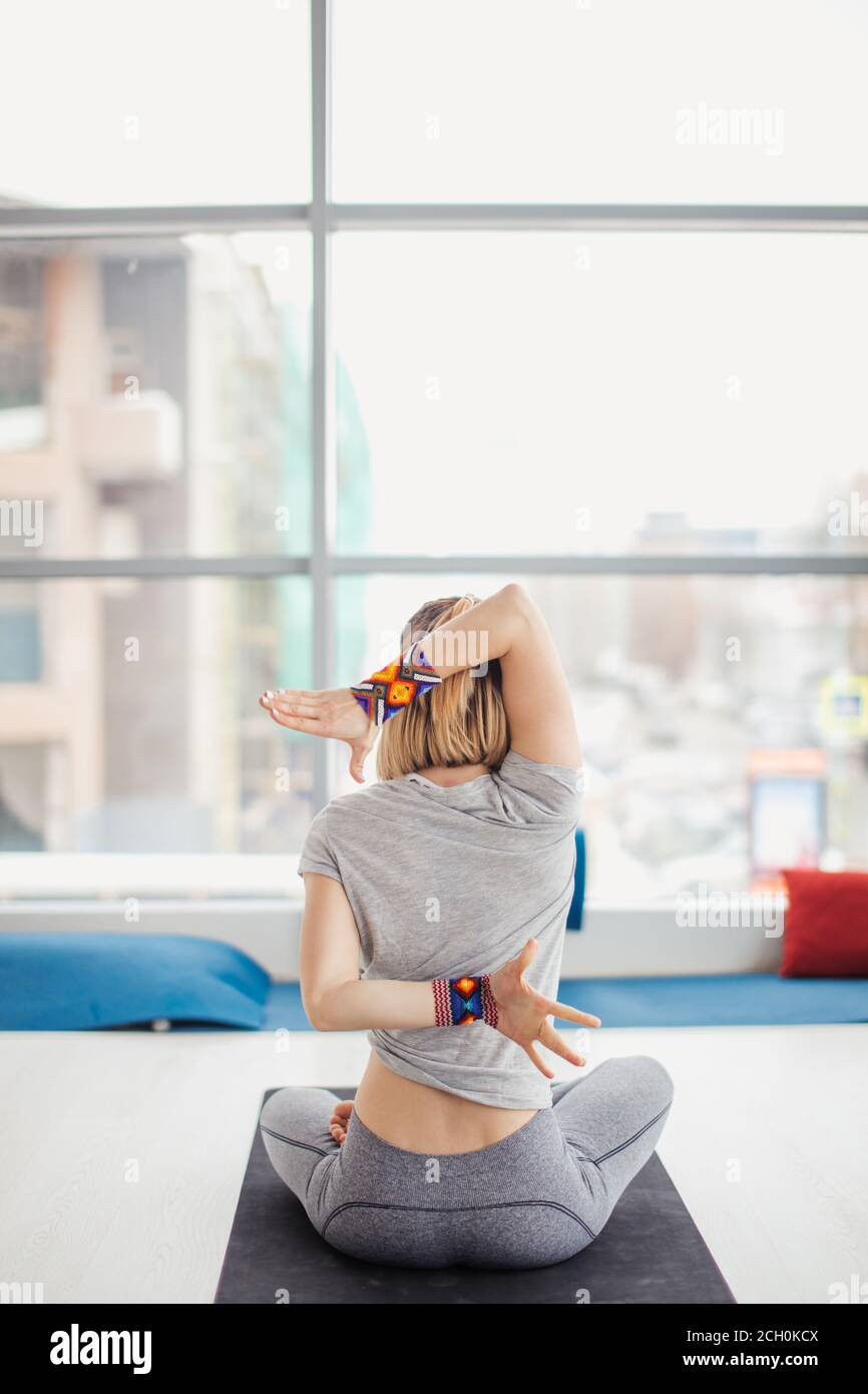 Rear view of sporty female practicing yoga lesson before big window ...